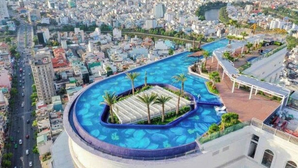 Piscina no terraço com um jardim central, rodeada por edifícios.