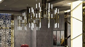 Um saguão moderno com balcão de recepção, uma cadeira vermelha e um lustre decorativo.