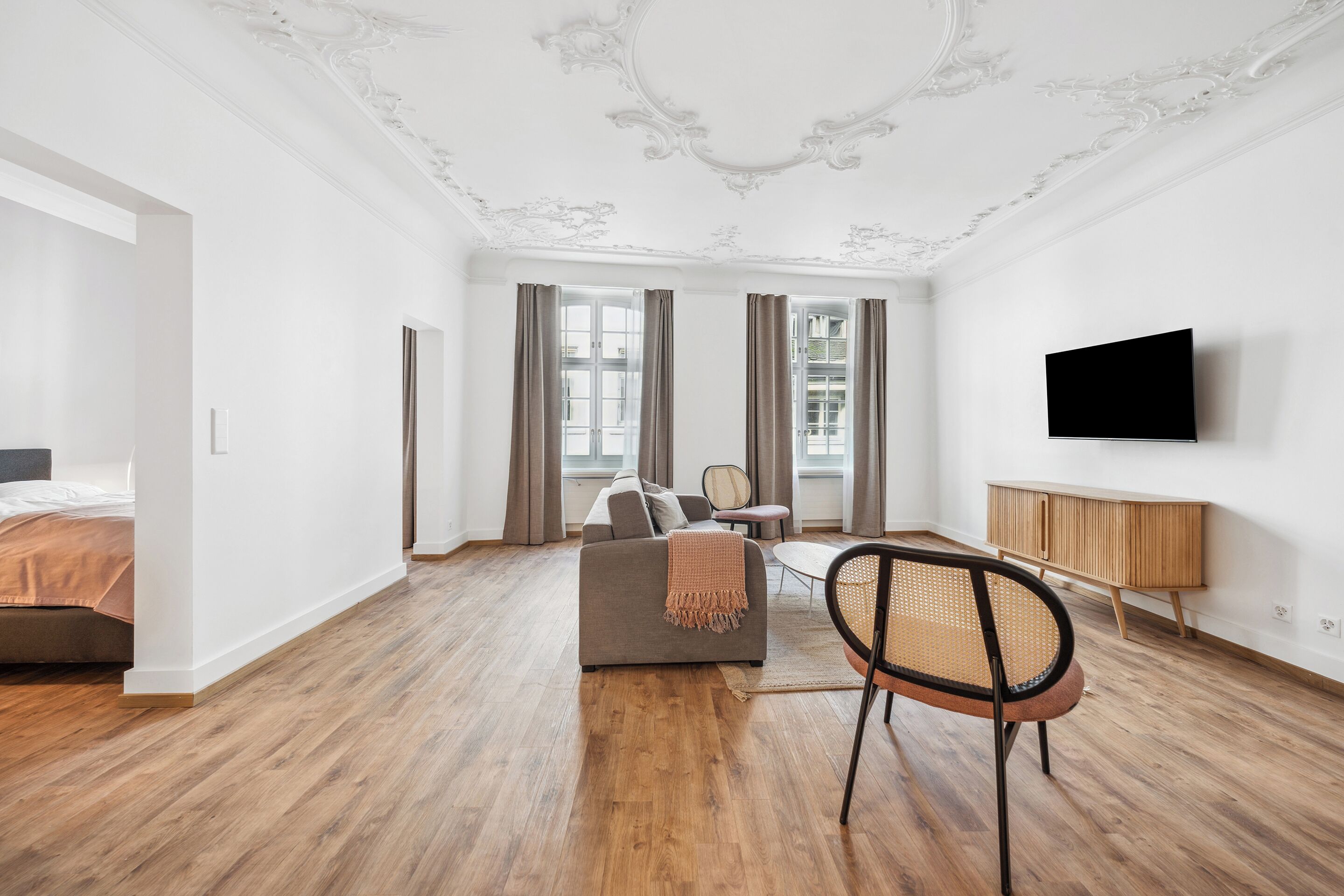 Uma sala de estar moderna com um sofá, uma poltrona, uma televisão e um armário de madeira.