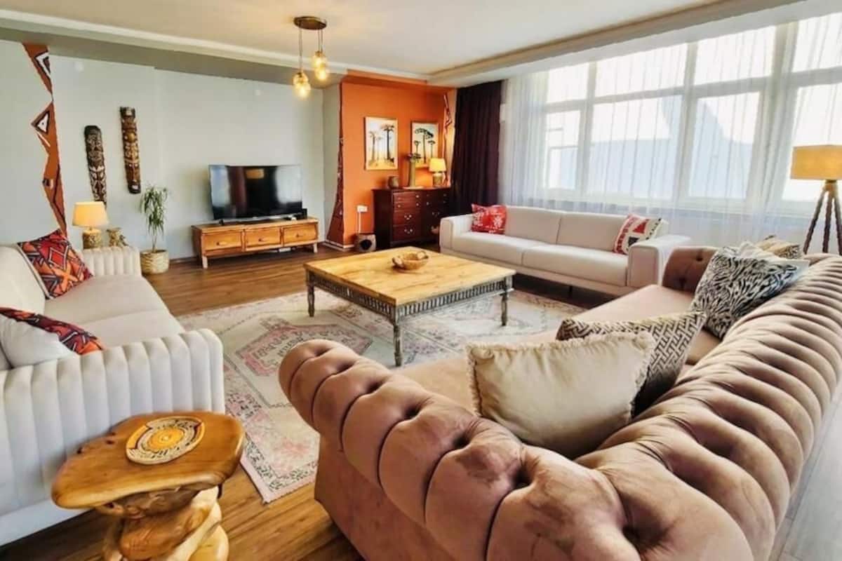 Sala de estar com sofá, poltrona, mesa de centro, televisão e objetos decorativos.
