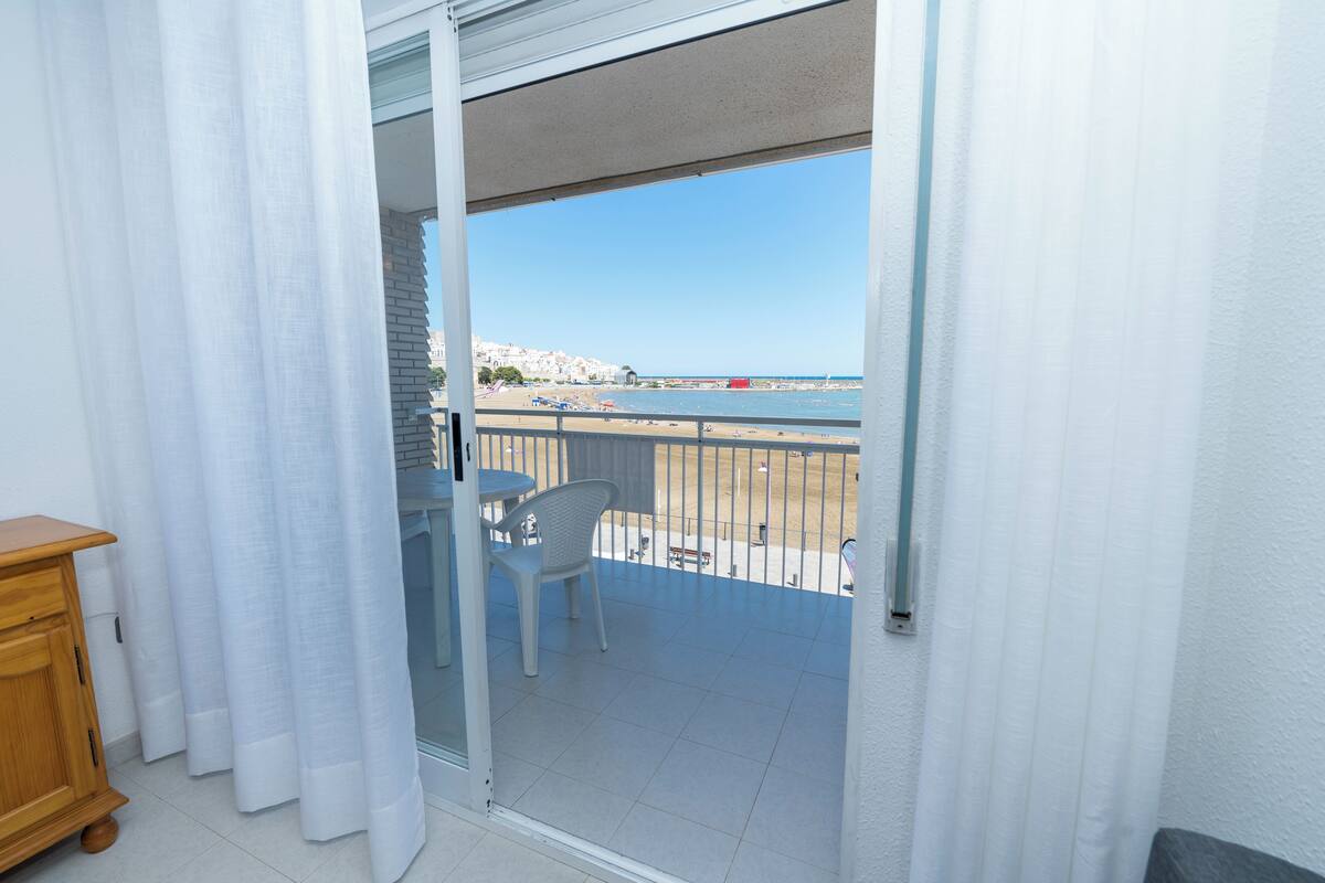 Uma varanda com vista para a praia e um espaço de refeições com mesa e cadeiras.