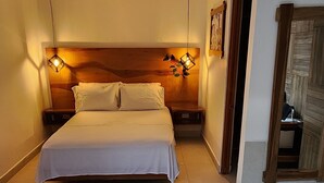 Quarto de hotel com duas camas, uma cabeceira de madeira, uma pequena mesa com uma toalha e uma banheira.