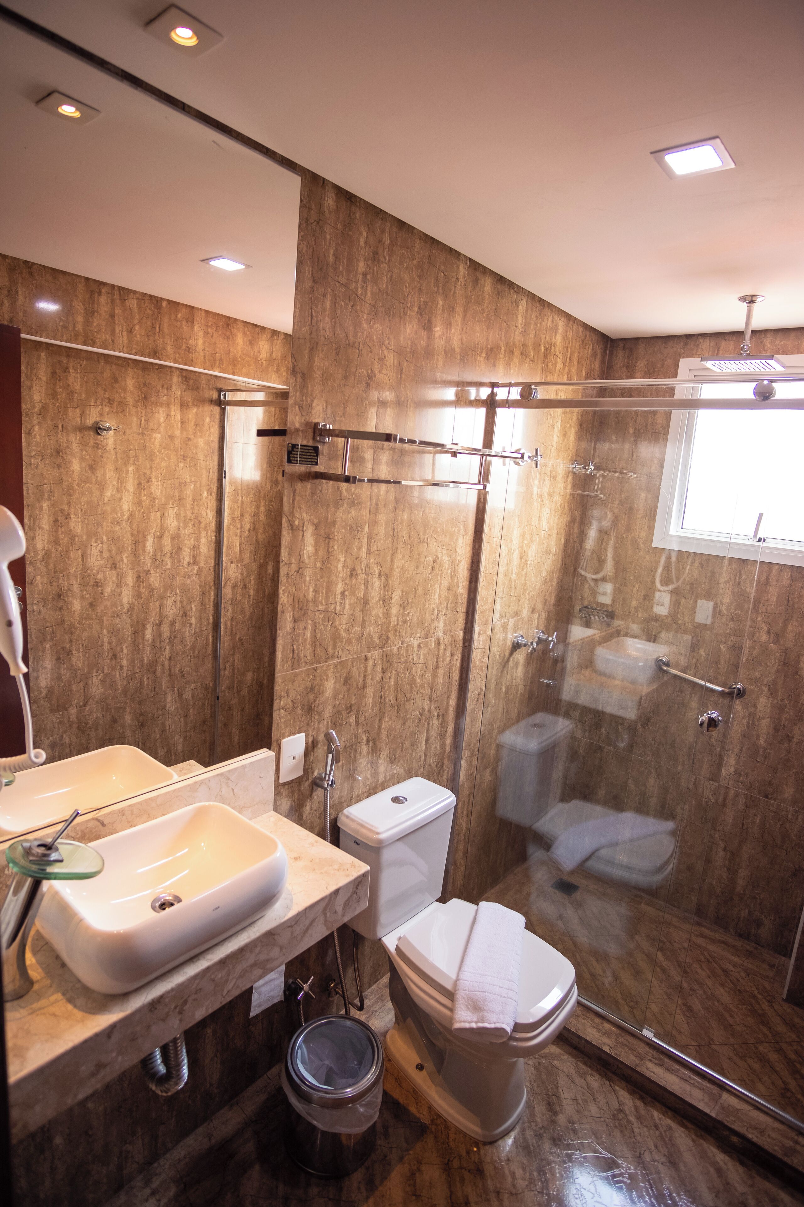 Uma casa de banho moderna com cabine de duche em vidro, uma sanita e uma pia branca.