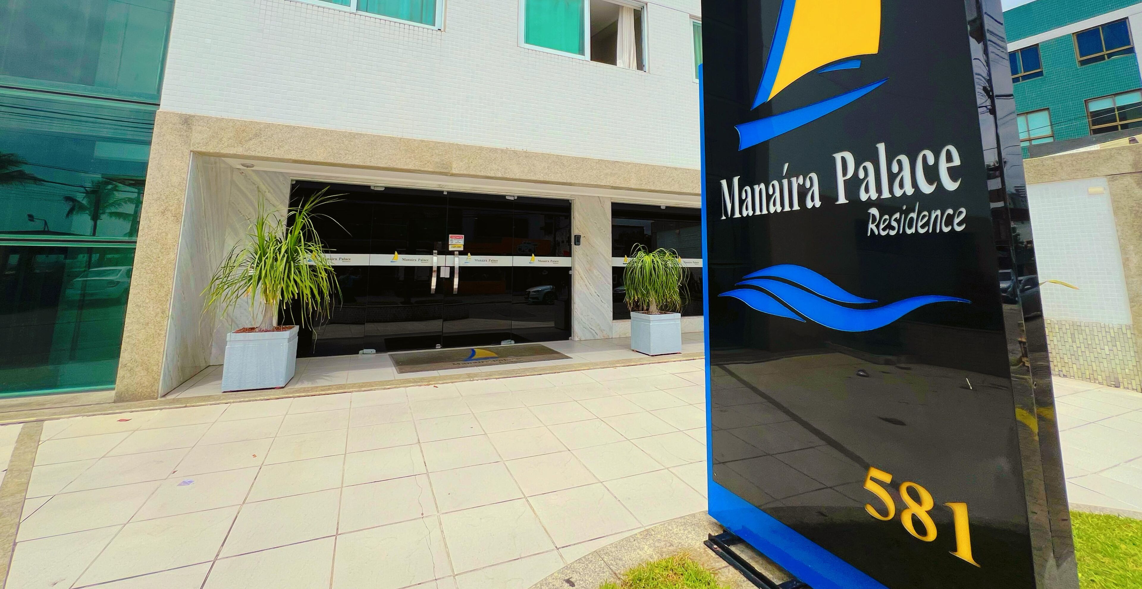 Entrada de um edifício com uma placa indicando "Manaira Palace Residence" e o número "581".