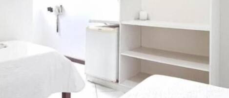 Quarto com cama, televisão na parede e guarda-roupa branco.