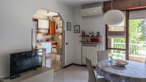 Uma cozinha moderna com área de refeições, TV e uma mesa com uma tigela e uma garrafa.