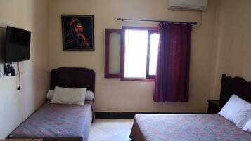 Quarto de hotel com duas camas, televisão, ar condicionado e janela com cortinas.