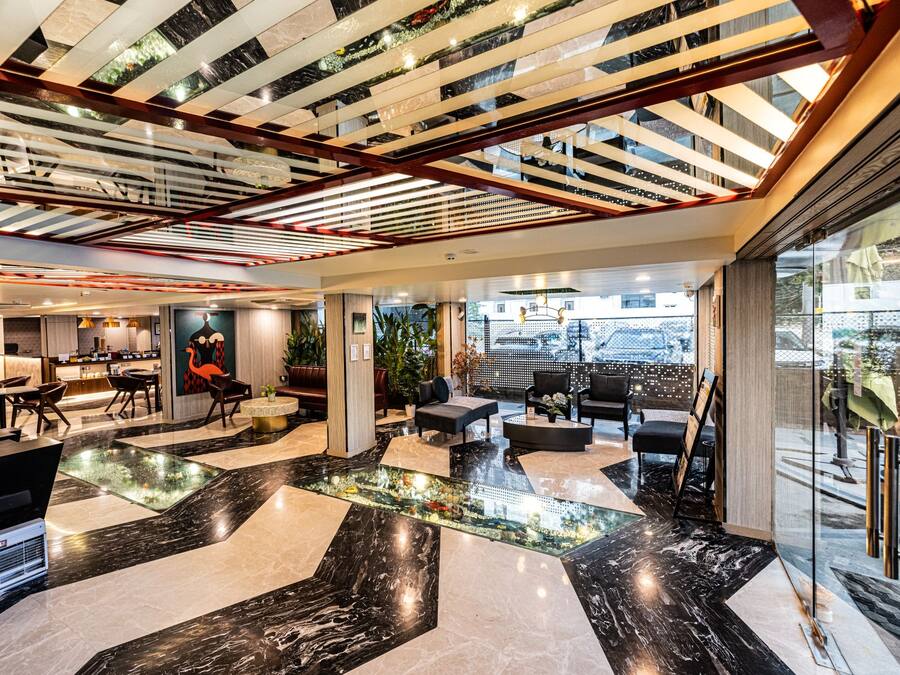 Um hall de hotel moderno com uma mesa de centro de vidro, área de estar e balcão de recepção.