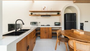 Cozinha moderna com ilha de madeira, bancadas brancas e geladeira preta.
