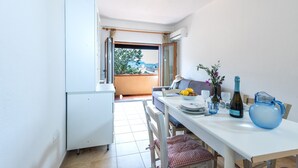 Cozinha compacta com área de refeições, varanda com vista e mesa posta com garrafa e jarra.