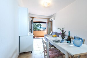 Cozinha compacta com área de refeições, varanda com vista e mesa posta com garrafa e jarra.