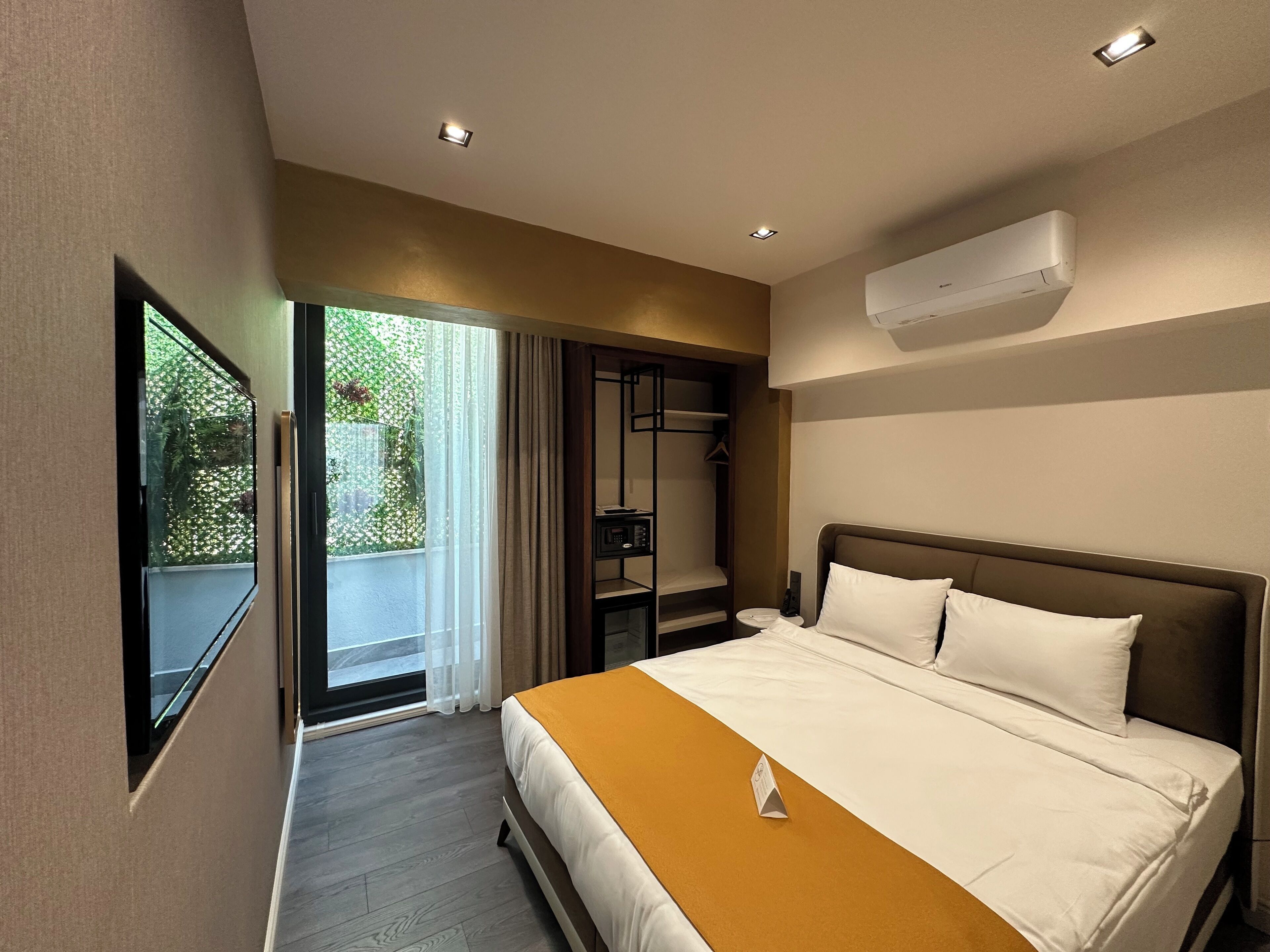 Quarto de hotel com cama, janela com vista, guarda-roupa e ar condicionado.