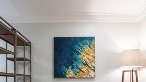 Um sofá cinzento, uma estante de madeira e um candeeiro de chão num quarto com soalho de madeira.