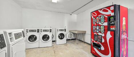 Uma lavanderia com várias máquinas de lavar e um refrigerador de Coca-Cola.