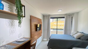 Quarto moderno com cama, sofá e área de refeições com cadeiras e mesa.