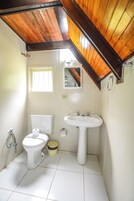 Casa de banho pequena e simples, com sanita, lavatório e espelho.