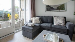 Uma sala de estar moderna com um sofá cinzento, um banquinho a combinar e uma mesa de centro com objetos decorativos.