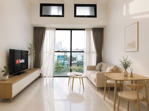 Uma sala de estar moderna com televisão, sofá, mesa de jantar e cadeiras.