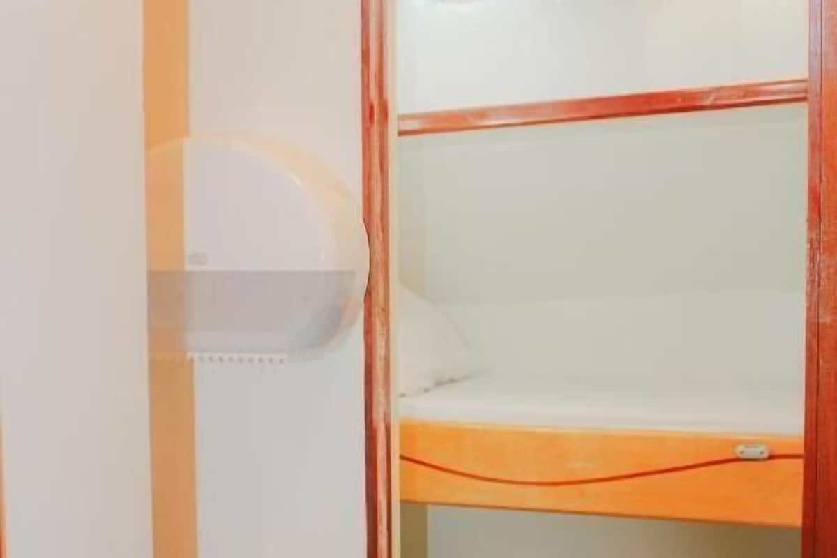 Casa de banho compacta com sanita, lavatório e beliche.