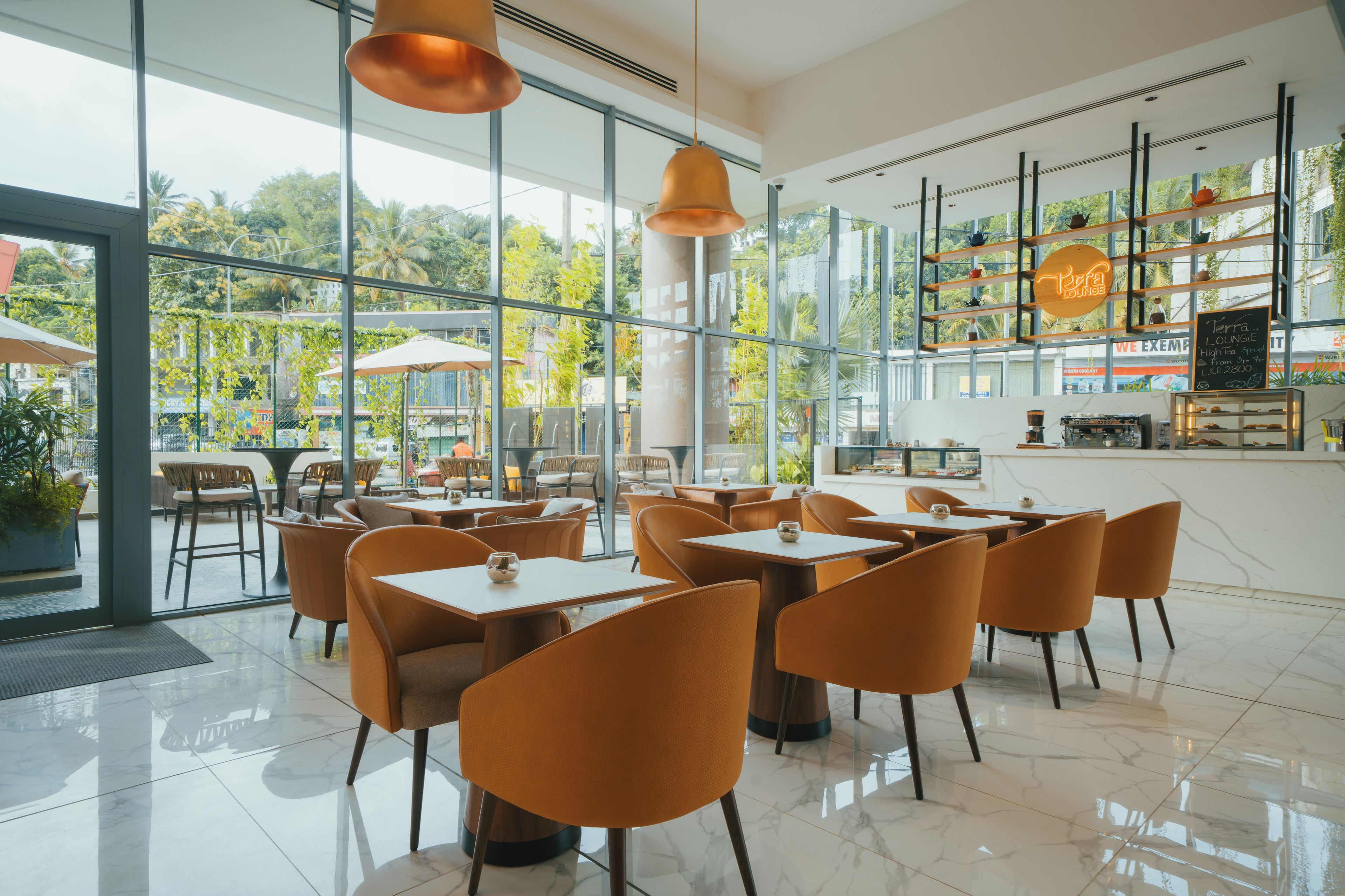 Um café moderno com interior amplo, grandes janelas e diversas opções de assentos.