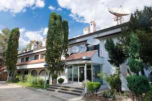 Um hotel com fachada branca, janelas em arco e antena parabólica.