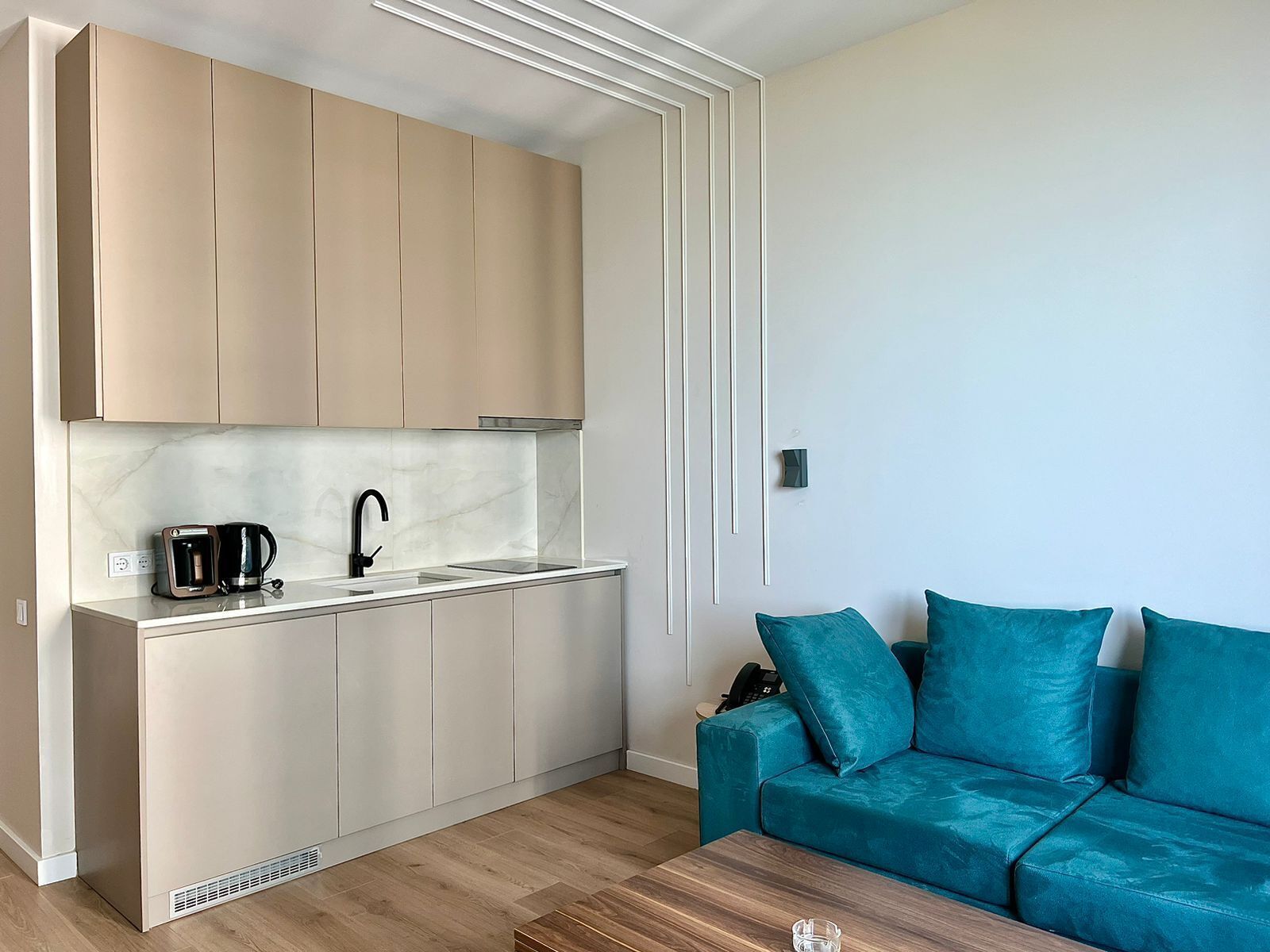 Um espaço compacto para viver, com cozinha compacta, sofá verde-azulado e mesa de centro de madeira.
