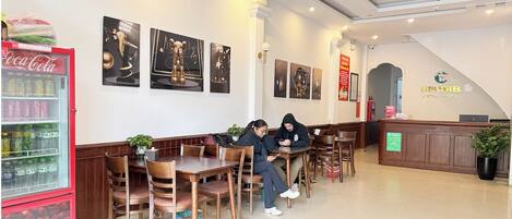 Um saguão de hotel com móveis de madeira, um refrigerador de Coca-Cola e obras de arte nas paredes.