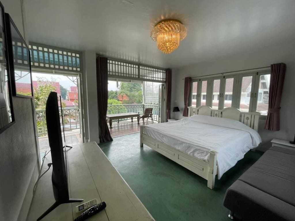 Quarto com uma cama grande, televisão e varanda com vista para edifícios.