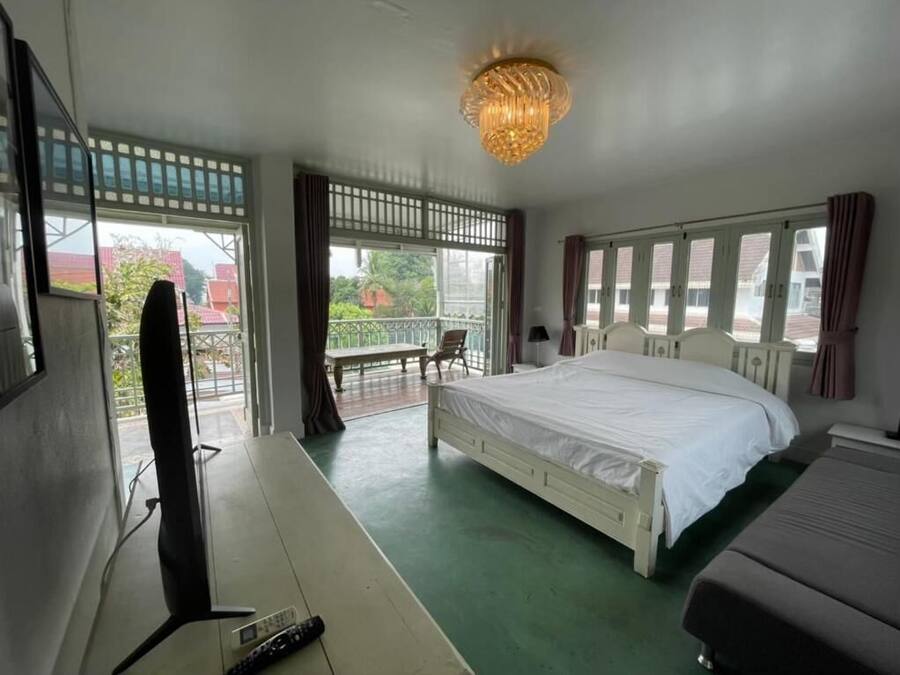 Quarto com uma cama grande, televisão e varanda com vista para edifícios.