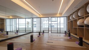 Estúdio de yoga com tapetes, blocos e espelho.