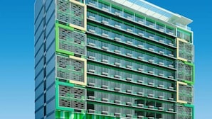 Um hotel moderno de vários andares, com fachada verde e branca, grandes janelas e área de entrada coberta.