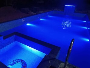 Piscina iluminada em azul com trampolim.