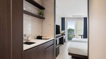 Quarto de hotel moderno com cozinha, cama e varanda com vista para a cidade.