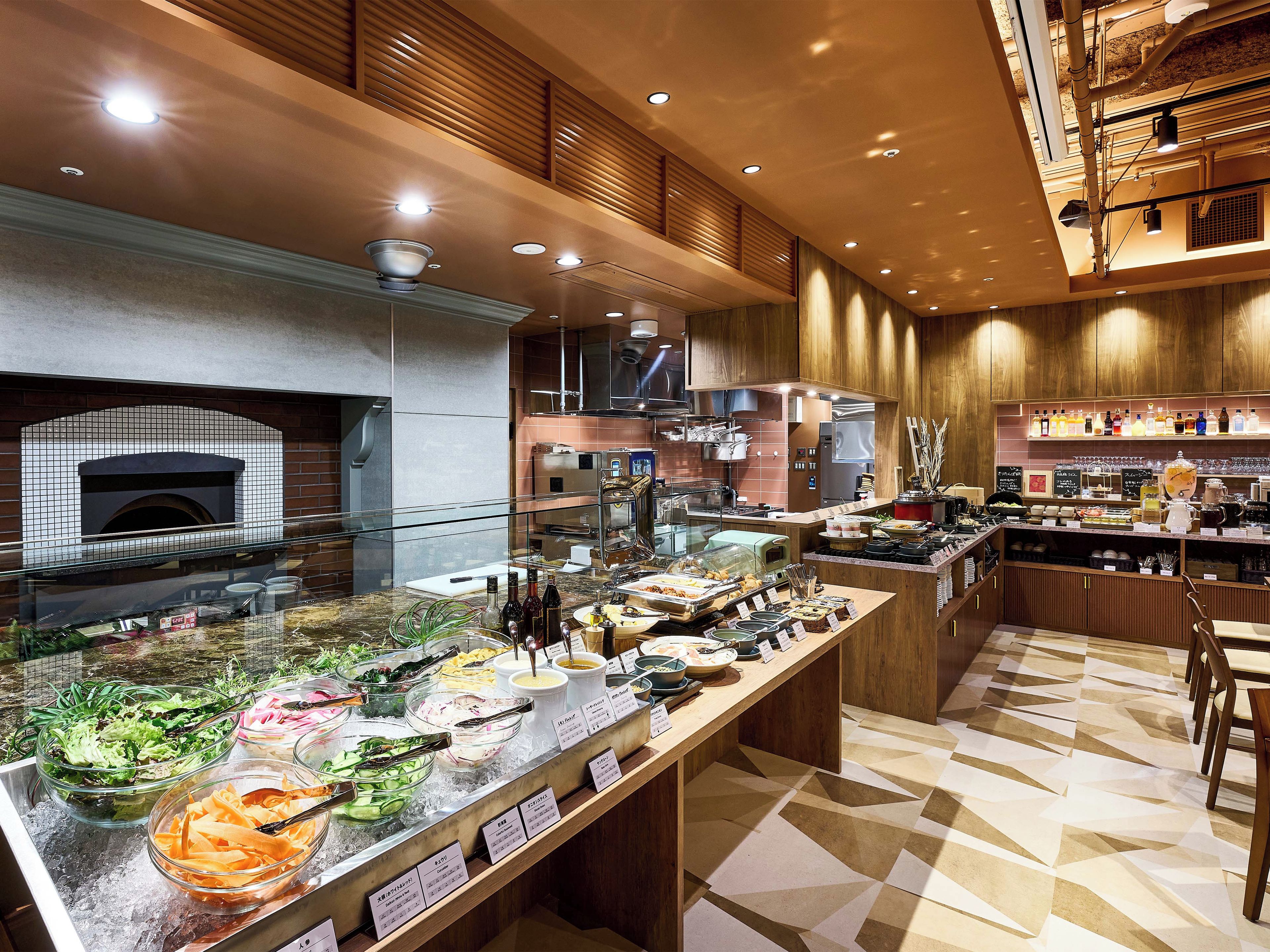 Espaço de buffet com diversas opções de comida e forno para pizza embutido.