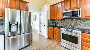 Cozinha com armários de madeira, eletrodomésticos de aço inoxidável e painel de backsplash de pedra.