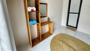 Quarto com guarda-roupa de madeira, espelho e tapete tecido.