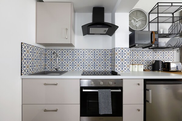 Uma cozinha com micro-ondas, forno e um relógio na parede.