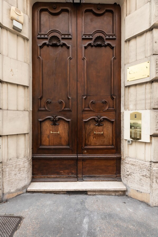 Uma porta de madeira grande e elaborada, com puxador de latão e uma placa acima.