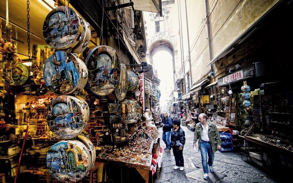 Uma rua estreita com lojas de ambos os lados, incluindo uma placa da Ferrara.
