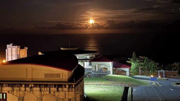 Um edifício costeiro com vista para o oceano e um pôr do sol.