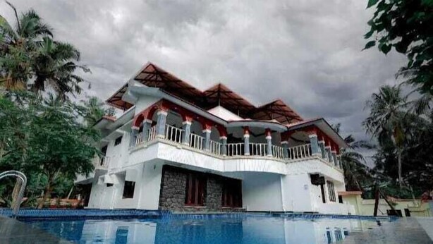 Um edifício de dois andares com piscina em frente.