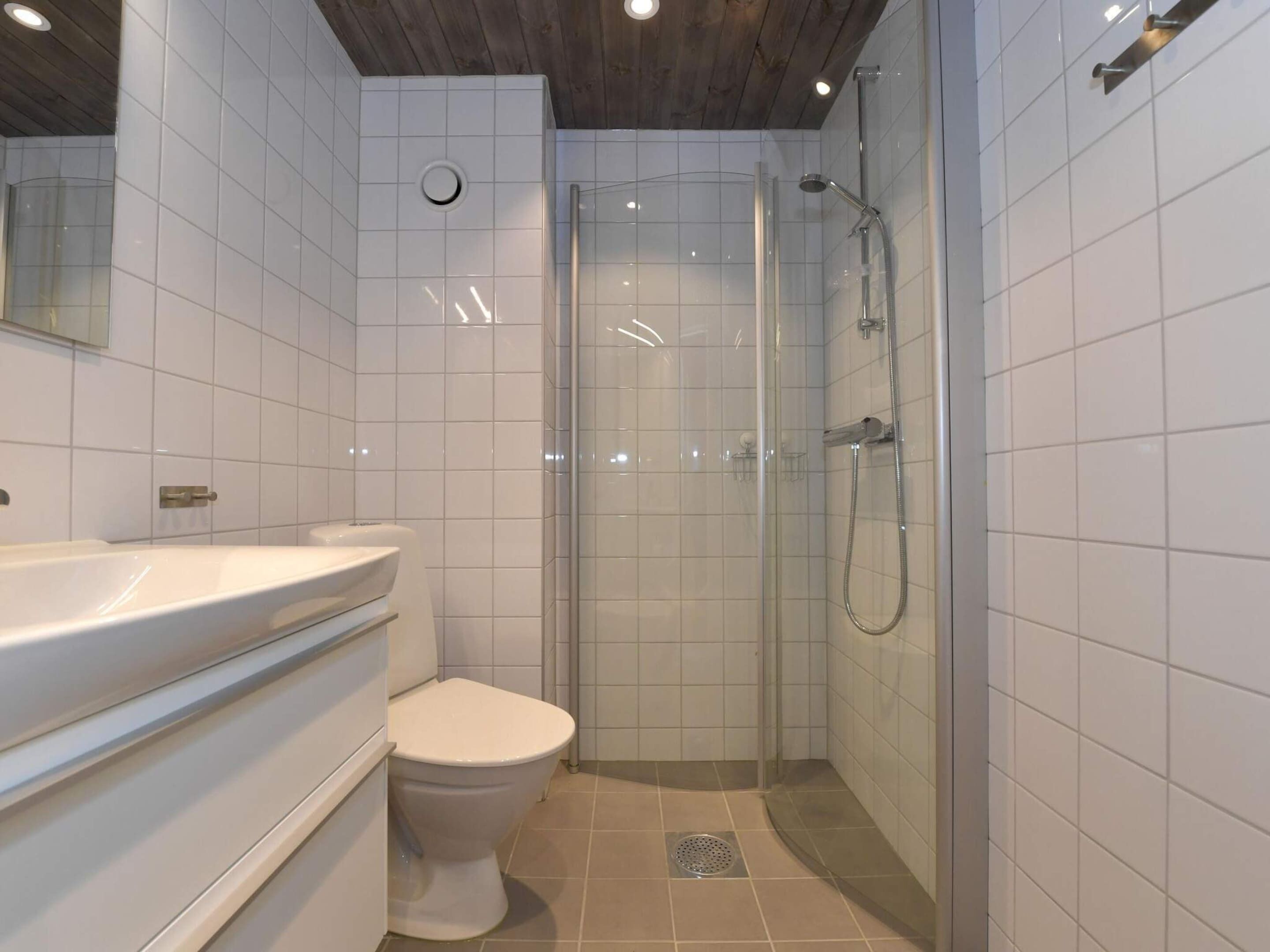 Casa de banho moderna com sanita branca, cabine de duche com vidro e lavatório branco.