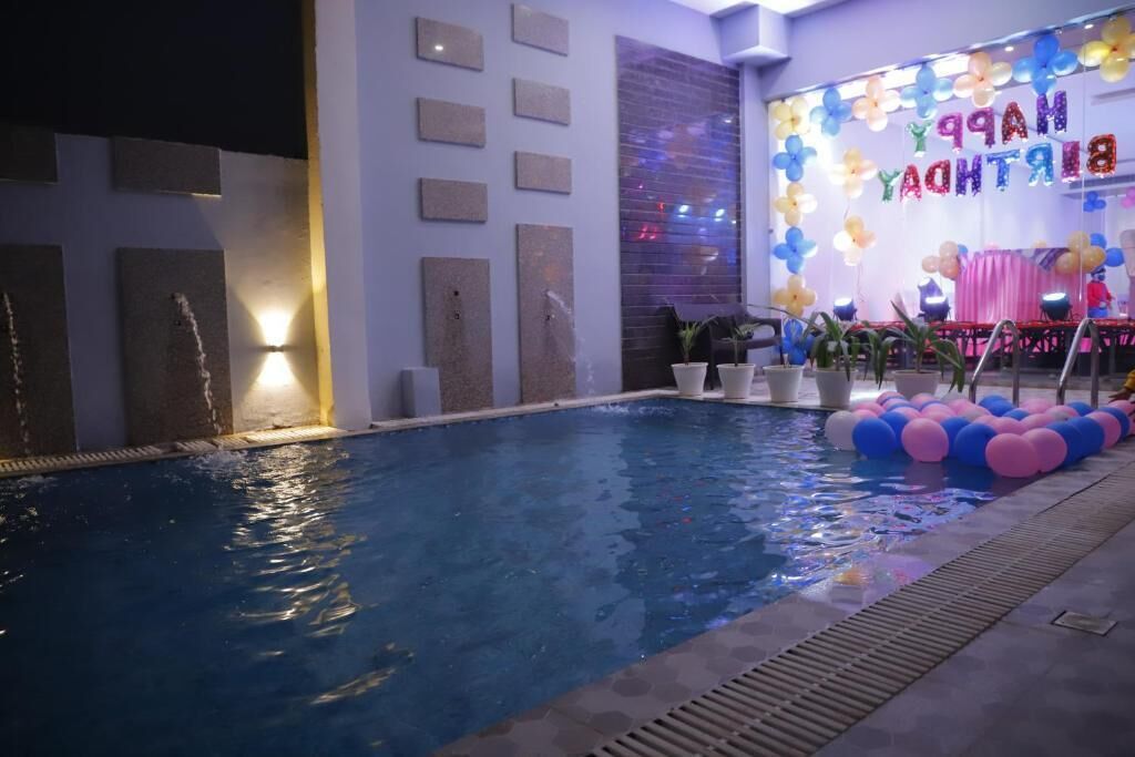 Piscina interna com faixa de 'Feliz Aniversário' e balões.