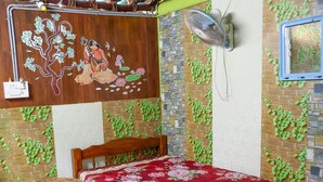 Quarto com cama de madeira, mesa de cabeceira trançada, ventoinha na parede e arte decorativa na parede.