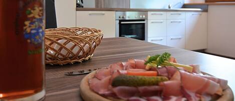 Uma mesa de jantar com um prato de fatias de carne, um copo de cerveja e uma cesta de palha.