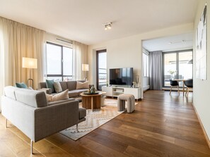 Uma sala de estar moderna com sofá, TV e área de jantar com cadeiras.