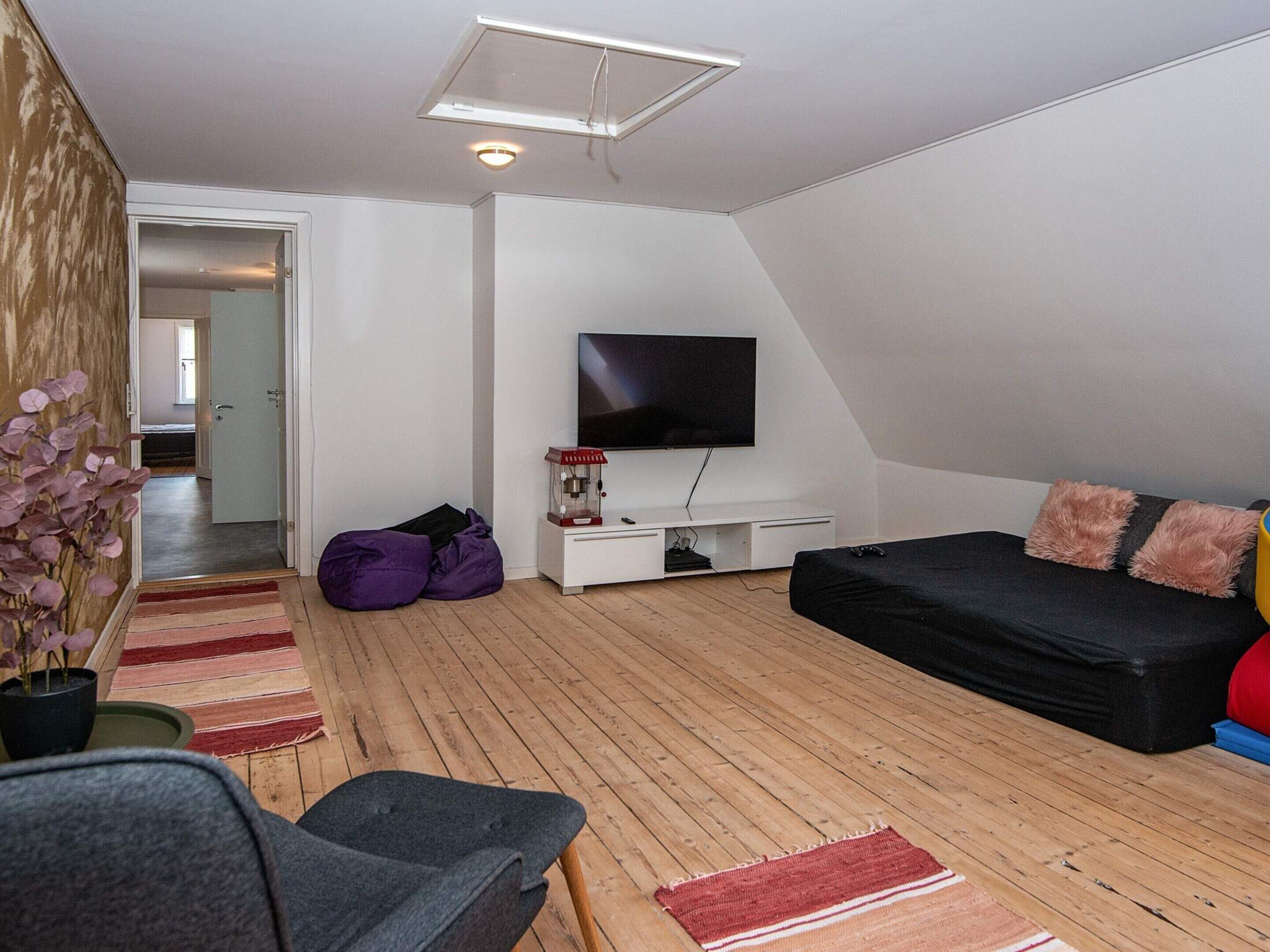 Uma sala de estar moderna com televisão de tela plana, sofá, mesa de centro e piso de madeira.