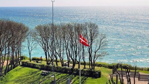 Um parque costeiro com um mastro, bancos e uma vista desobstruída do mar.