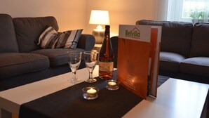 Sala de estar com sofá, mesa com garrafa de vinho, copos e velas.