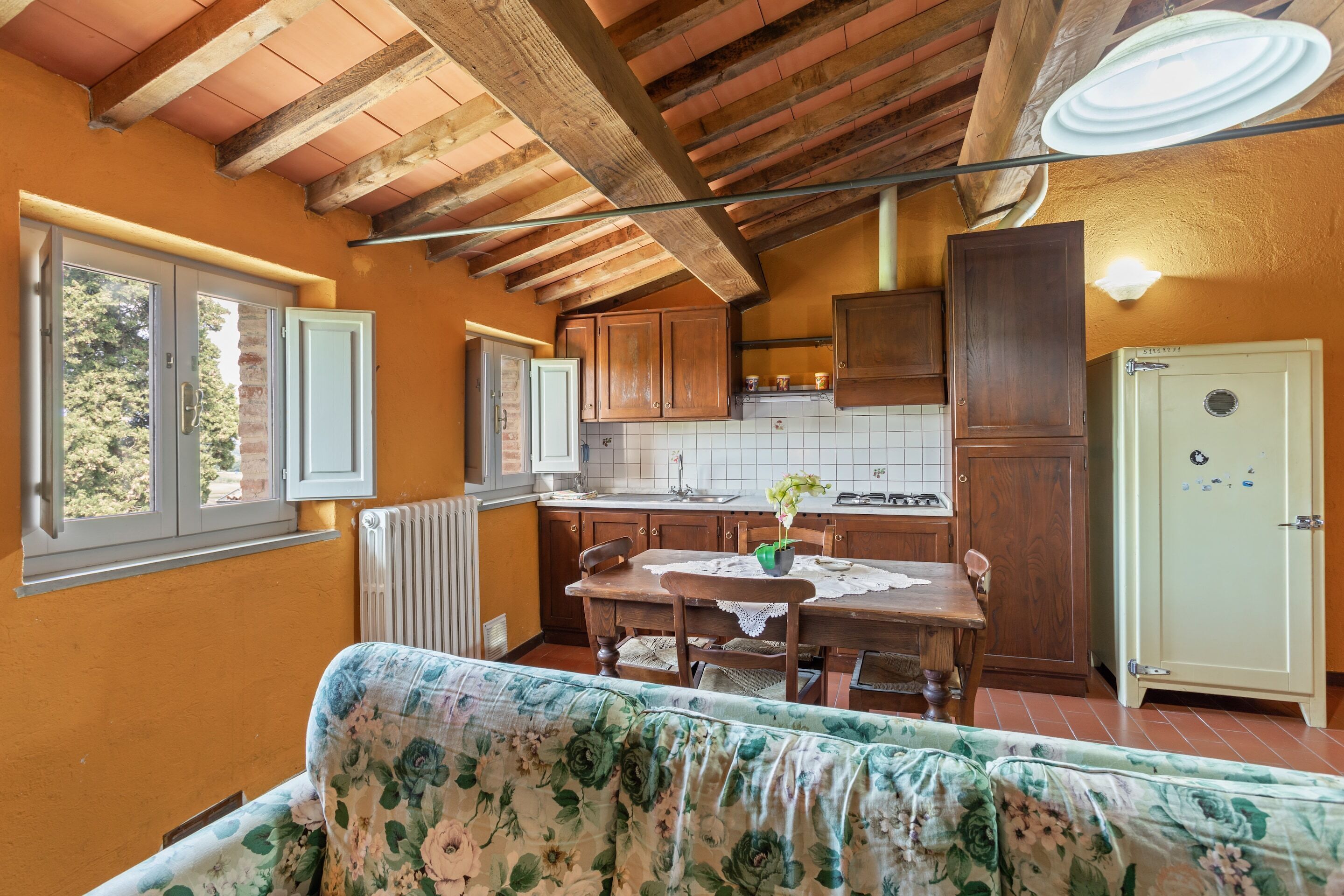 Cozinha acolhedora com armários de madeira, uma mesa de jantar e um radiador.